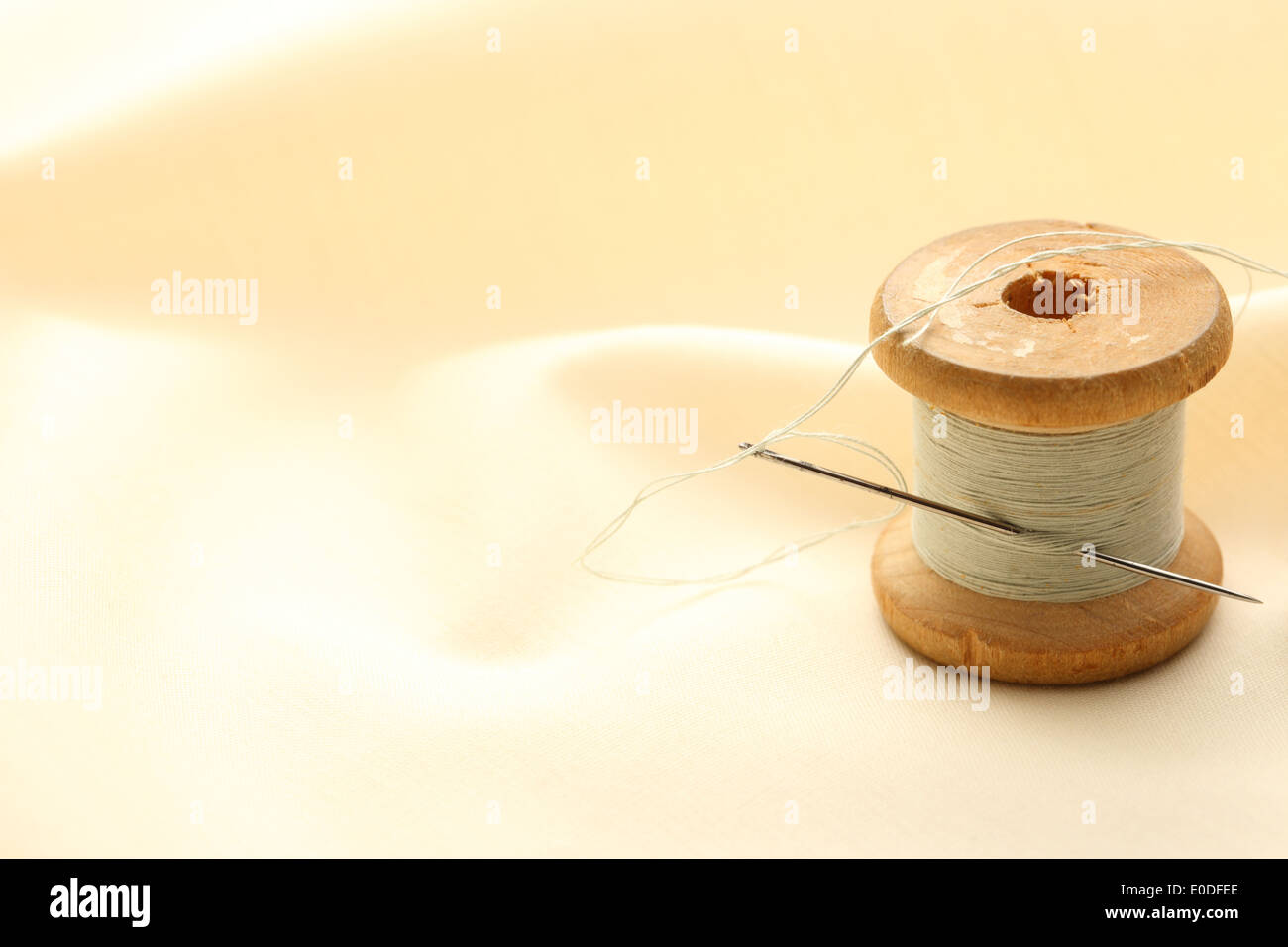 Sewing bobbin and needle on silk cloth Stock Photo - Alamy