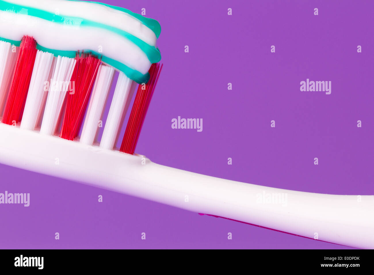 A pink toothbrush with toothpaste on a purple background Stock Photo ...