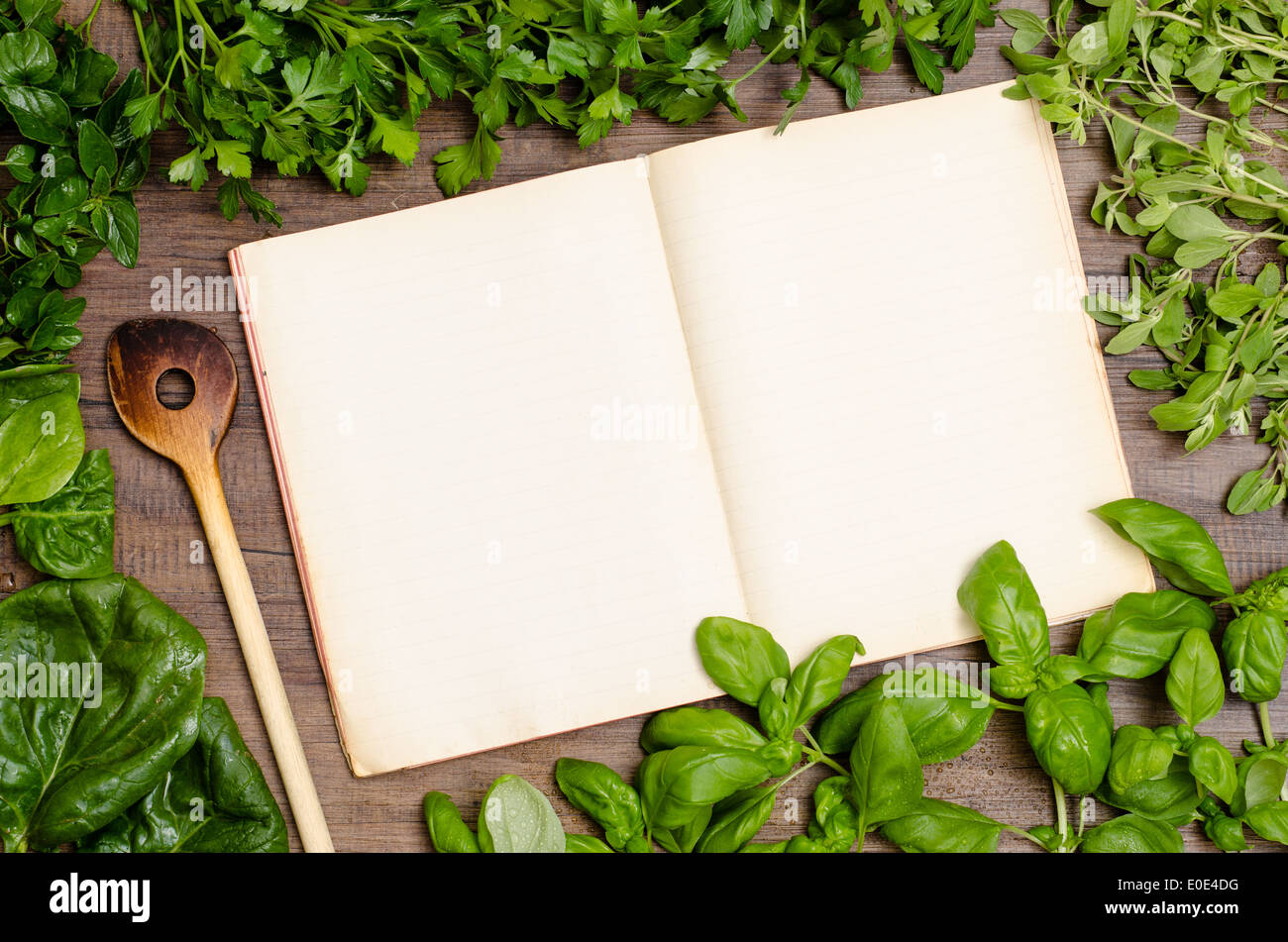 Book for recipes with wooden spoon and green herbs Stock Photo - Alamy