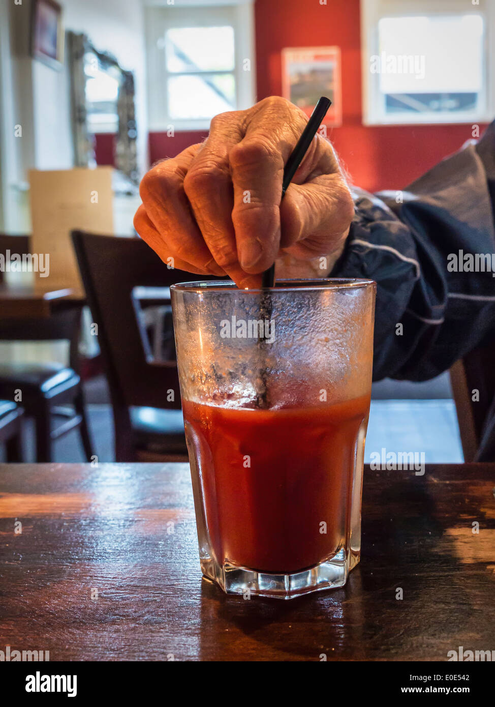 Hand stirring half full glass of tomato juice with a straw Stock Photo ...