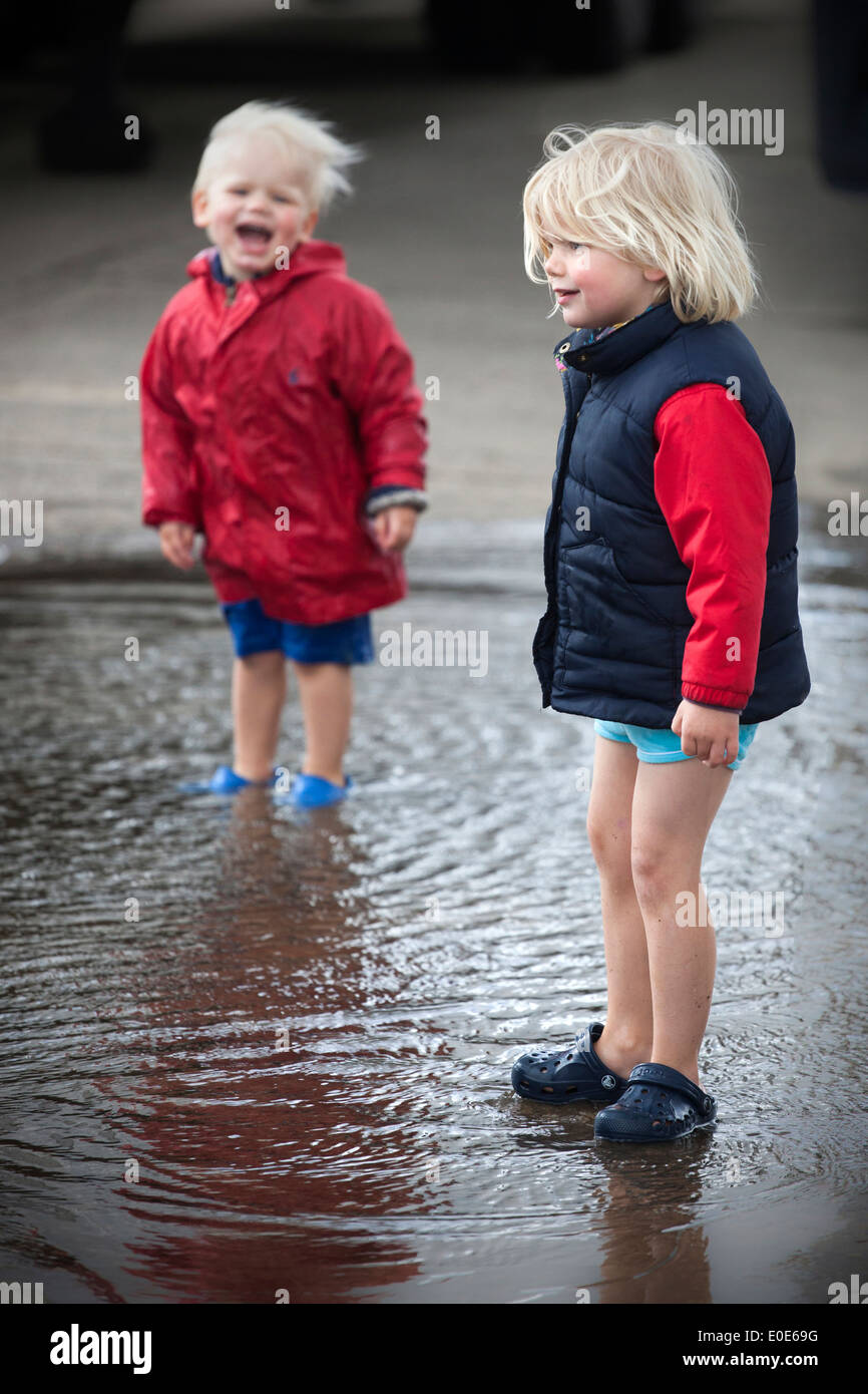 Two young boys playing and splashing in a puddle Stock Photo - Alamy