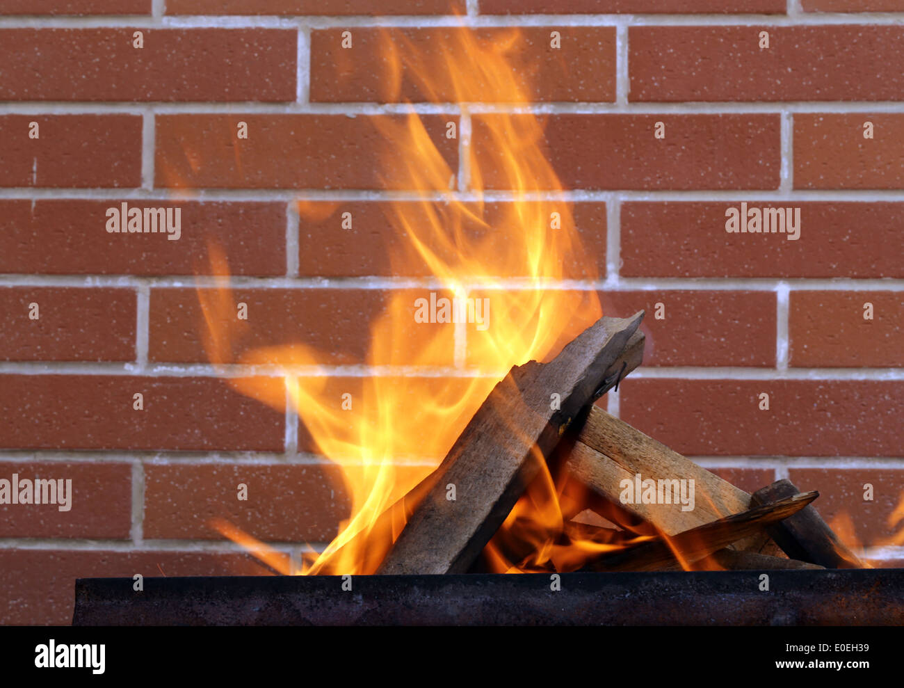 burning wood in a brazier on the brick wall background Stock Photo - Alamy