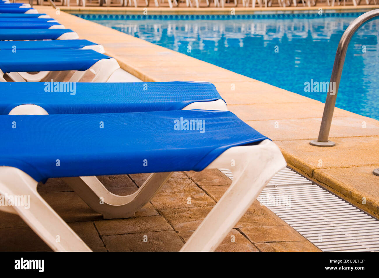 Blue sunbeds surrounding a swimming pool Stock Photo - Alamy