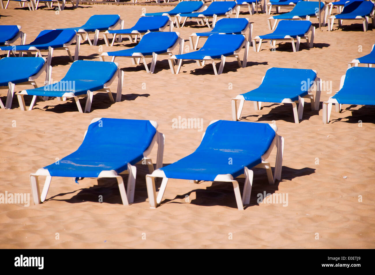 Blue sunbeds in the sand Stock Photo - Alamy