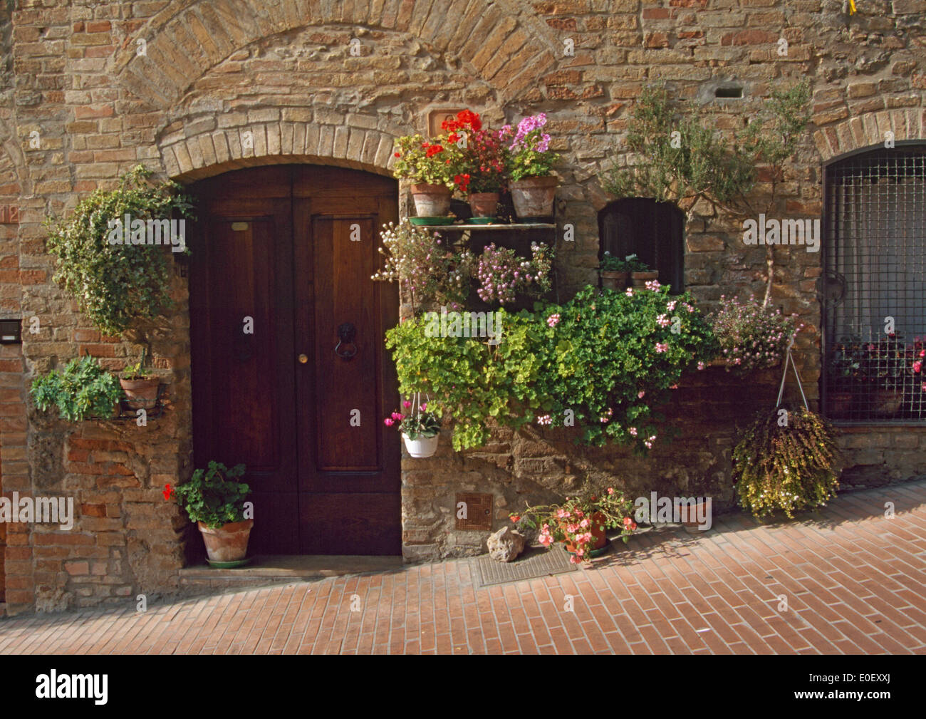 Facade of brick house with flowers, San Gimignano, Italy Stock Photo ...