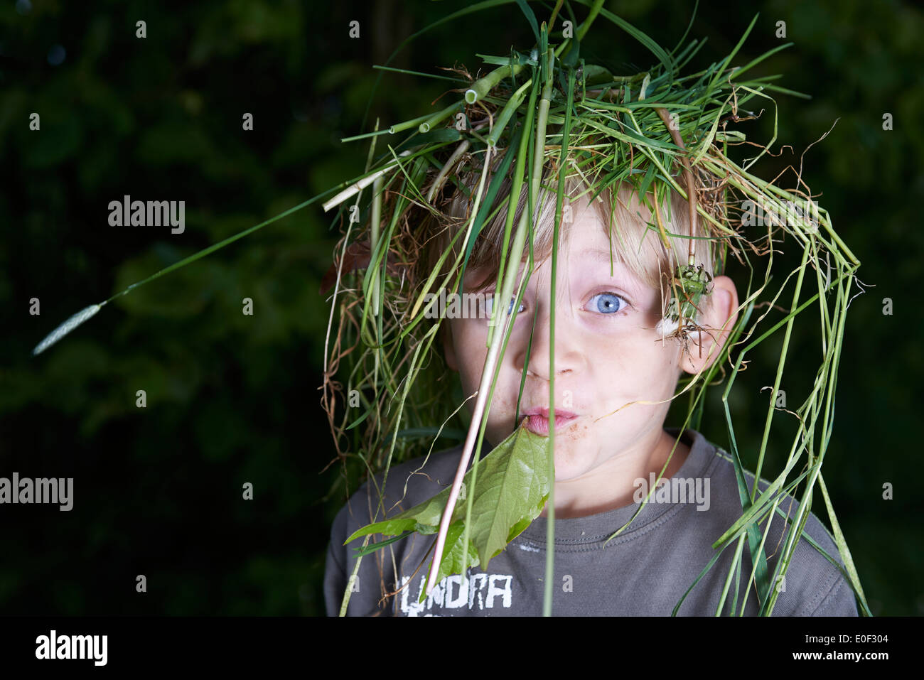 A Portrait of Child blond boy with grass on his head, making fun Stock ...