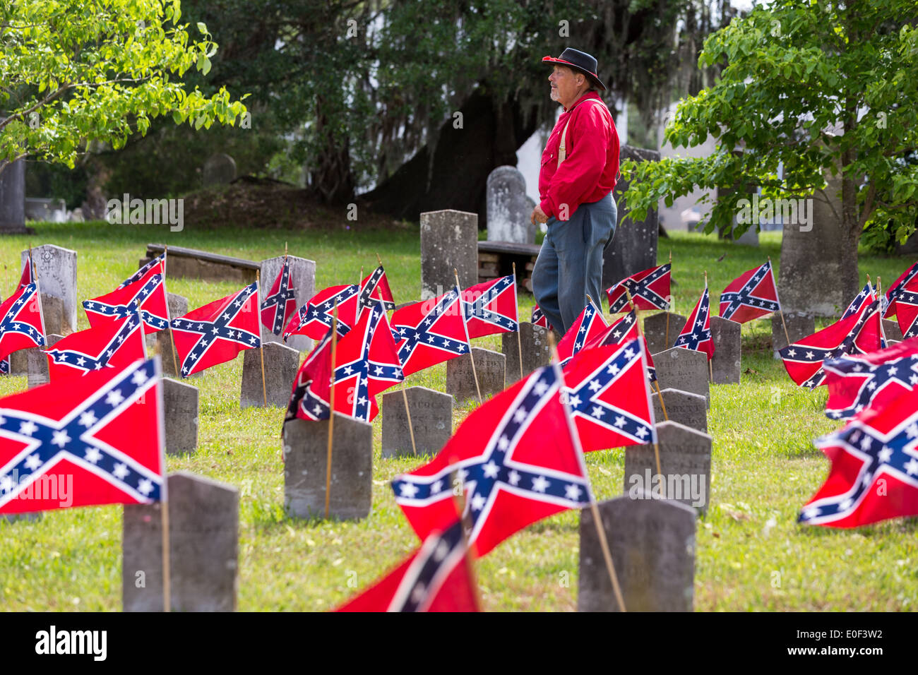 A Civil War re-enactor walks past rebel flags decorating grave markers ...