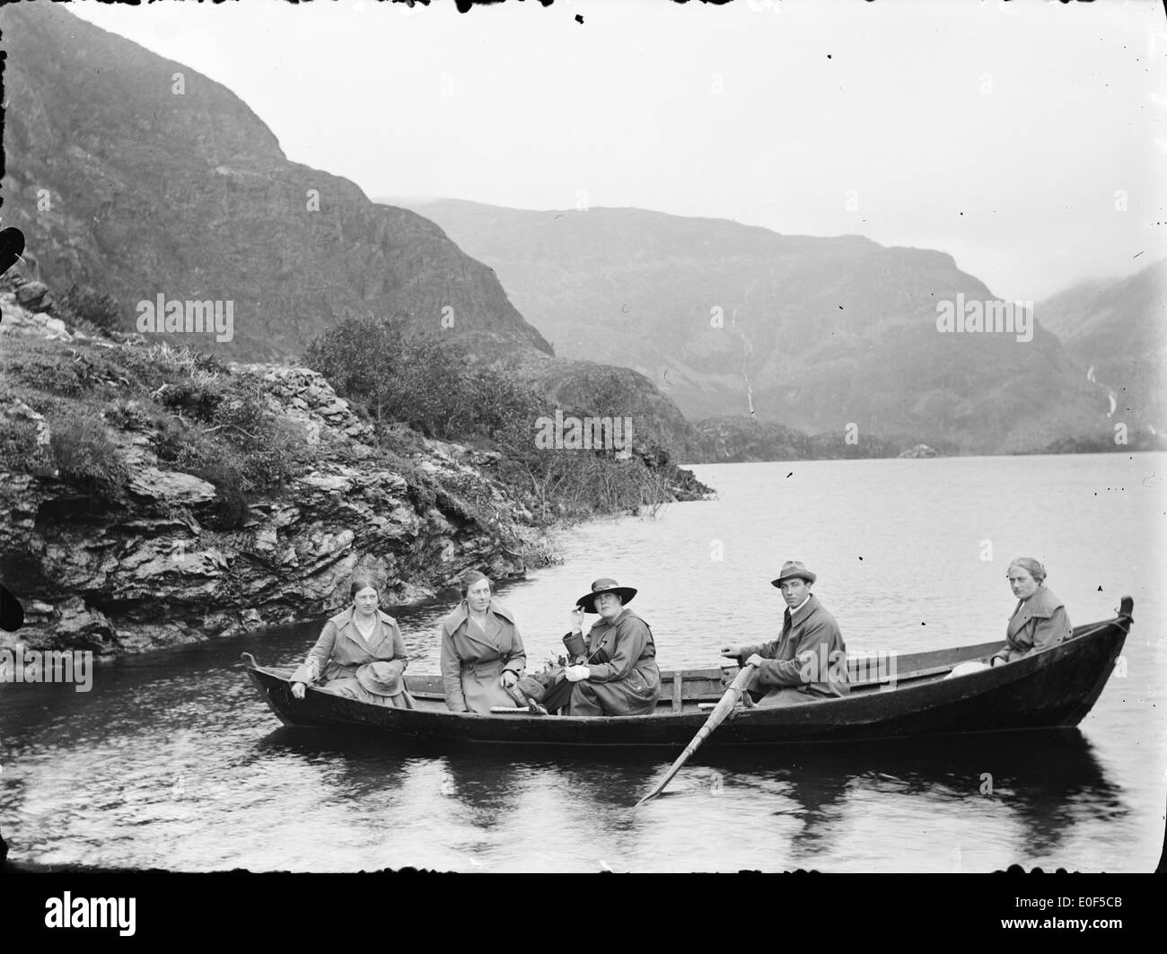 A historic photograph of a group of people rowing a boat in Sogn og ...