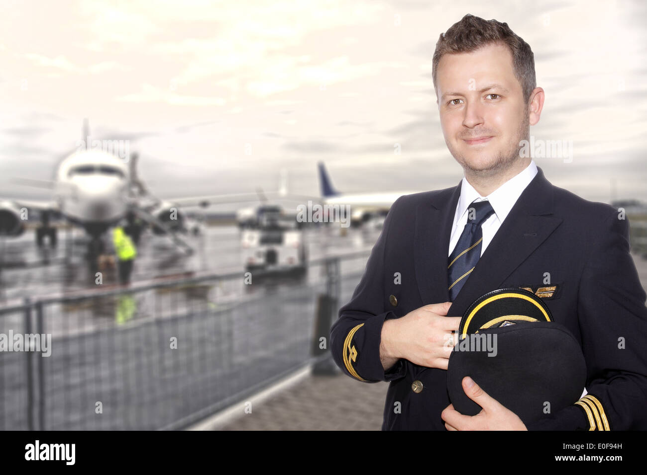 A smiling pilot in uniform on the tarmac airport Stock Photo - Alamy