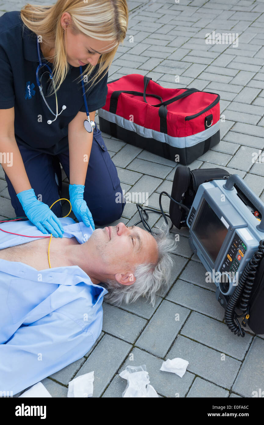 Paramedic examining unconscious elderly patient lying on street Stock ...