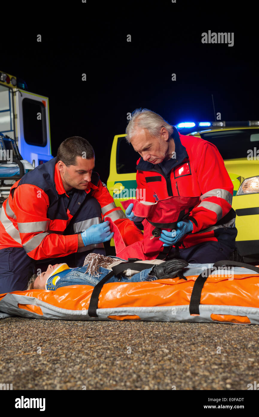Paramedic team giving firstaid to injured woman at night Stock Photo ...