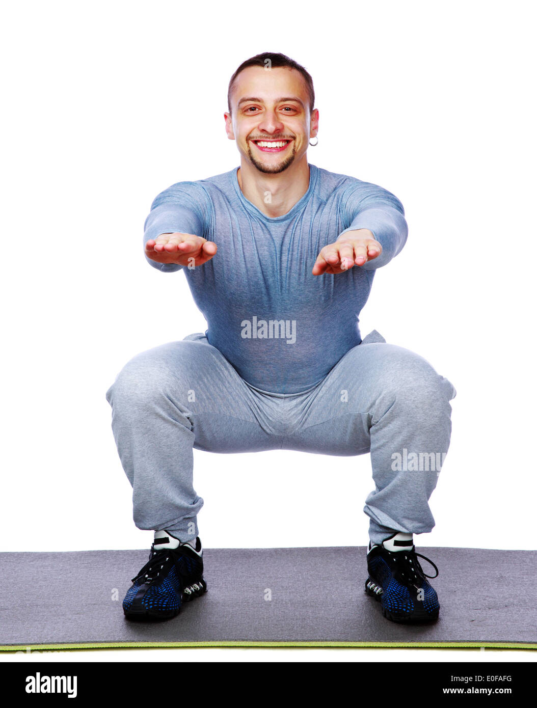 Happy fit man doing squats over white background Stock Photo - Alamy