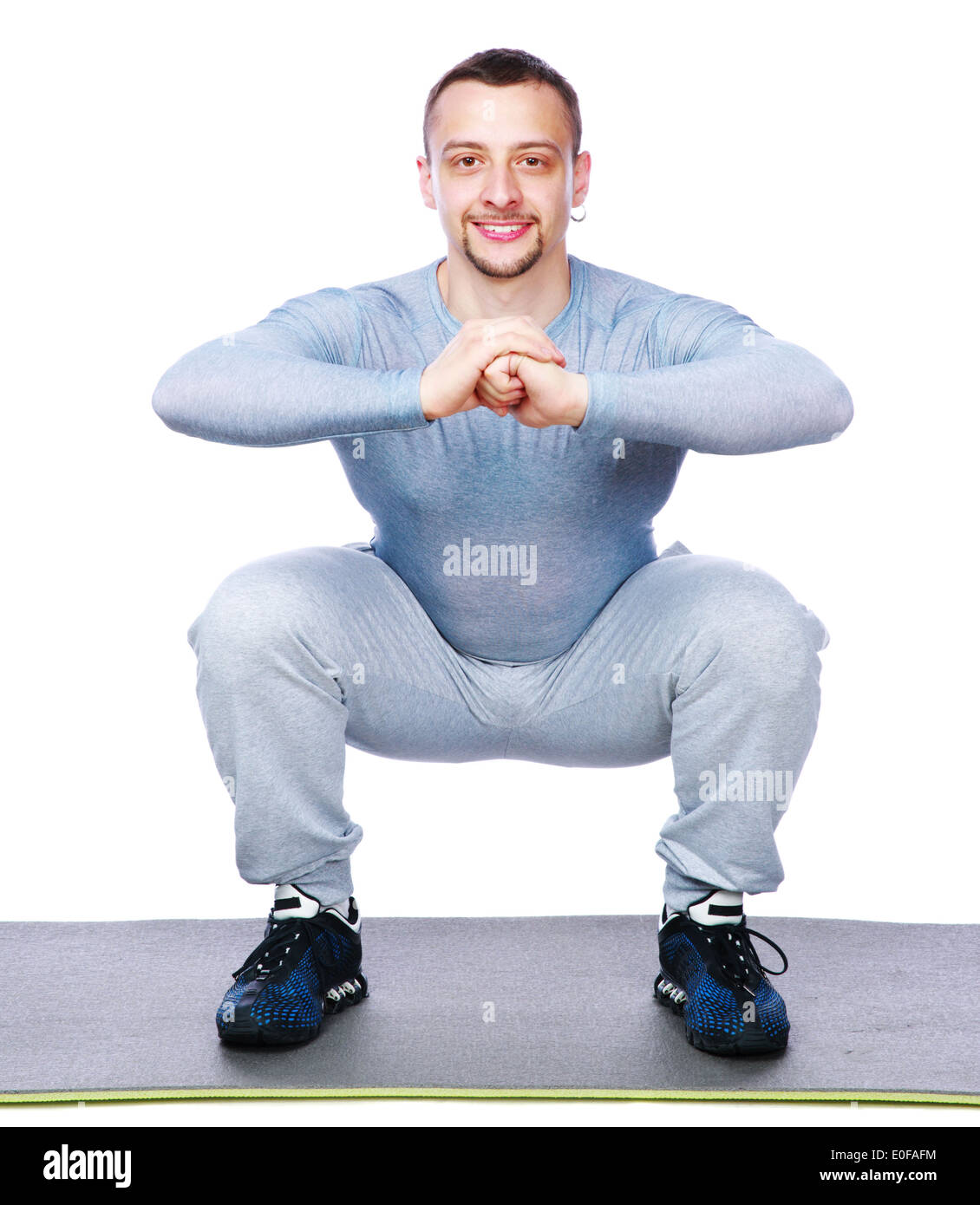 Fit man doing squats over white background Stock Photo - Alamy