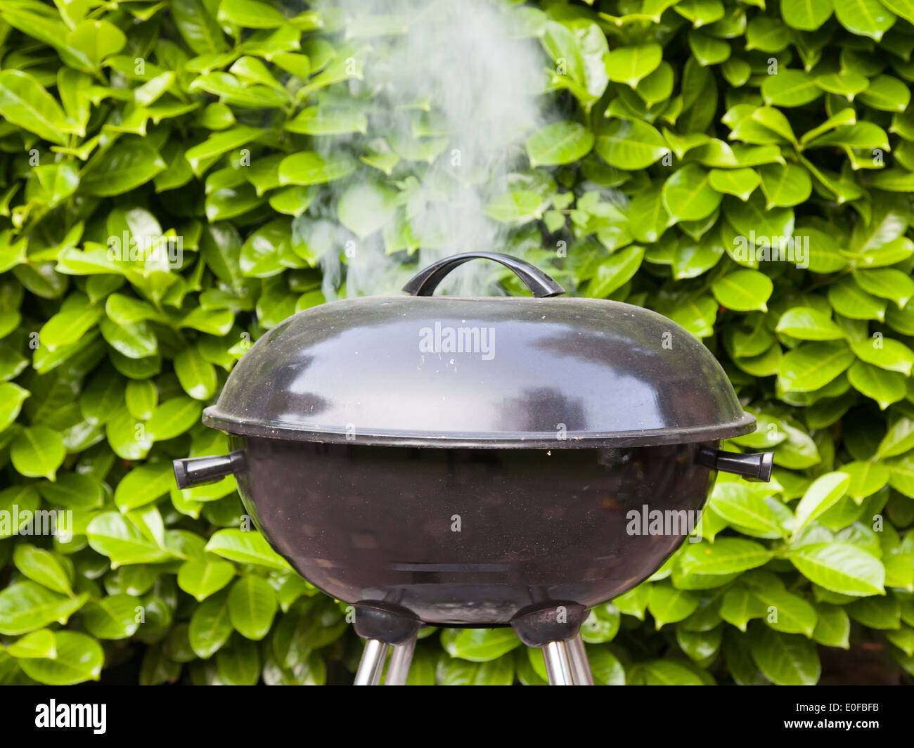 Old black barbecue being used, smoke coming from the top Stock Photo ...