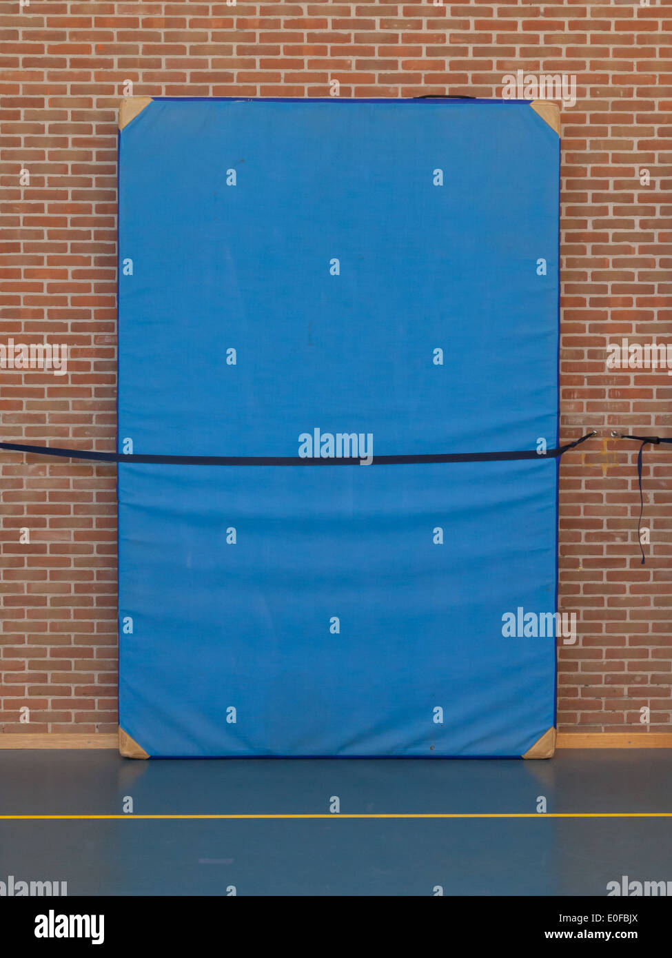 Large blue mat strapped to a brick wall, gym Stock Photo - Alamy