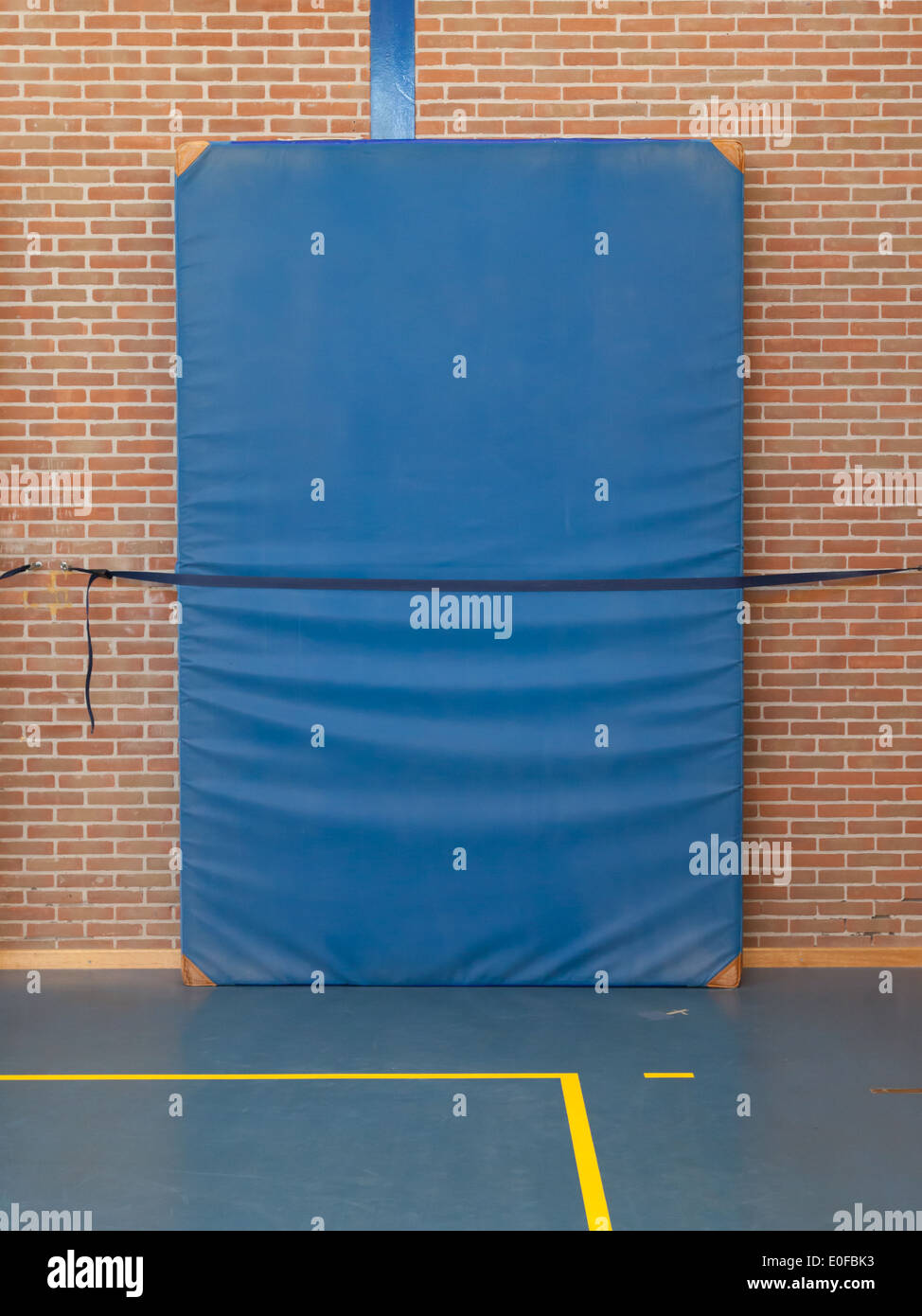 Large blue mat strapped to a brick wall, gym Stock Photo - Alamy