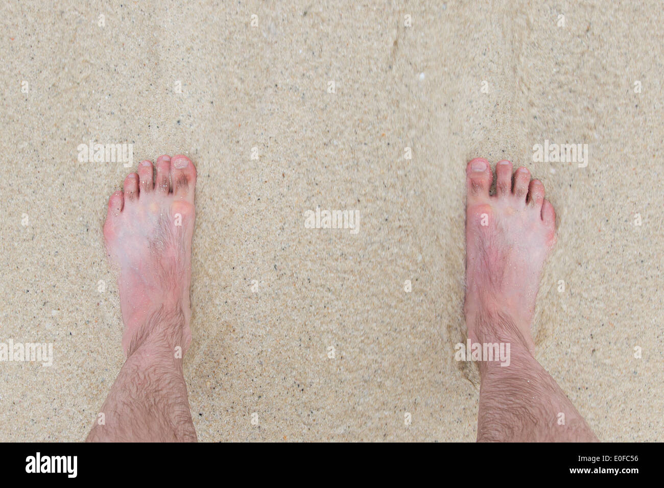 Fast wave comes in, feet standing still on a beach Stock Photo - Alamy