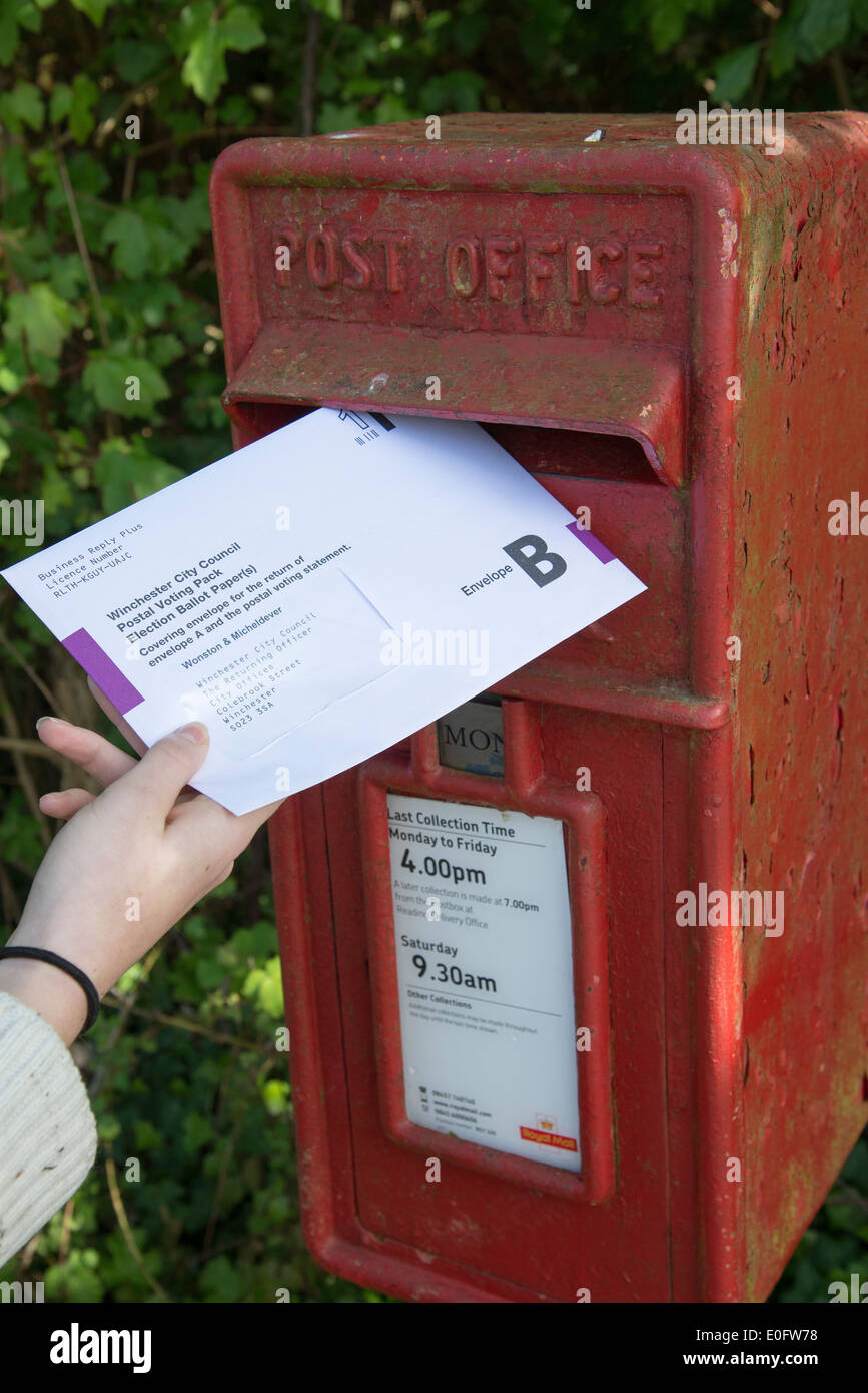 Postal vote envelope being placed into a letter box Envelope containing ...