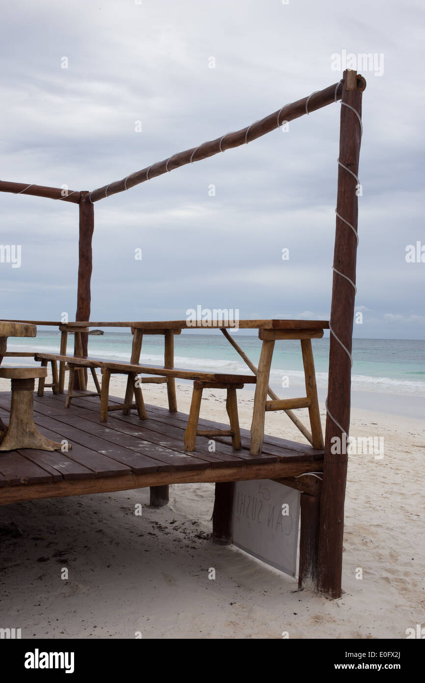 Wooden bar structure on beach with stools and table facing ocean on ...