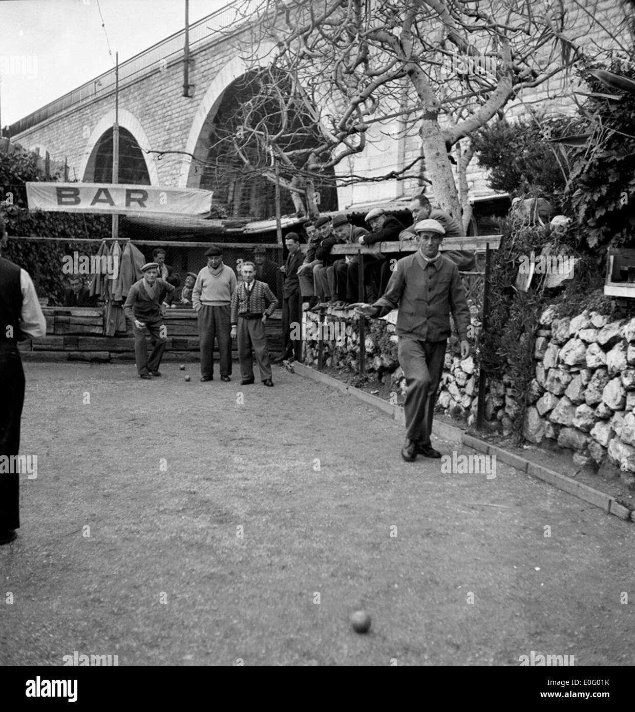 This image captures a group of men playing boules (a French bowling ...