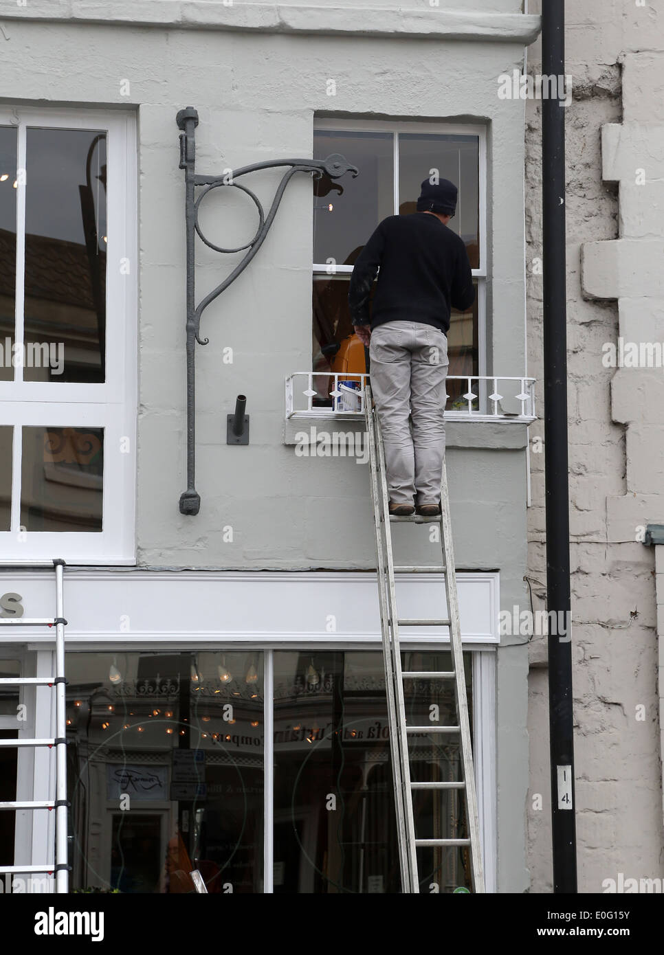 Man decorating a first floor window over a store front, Bath, 10 April ...