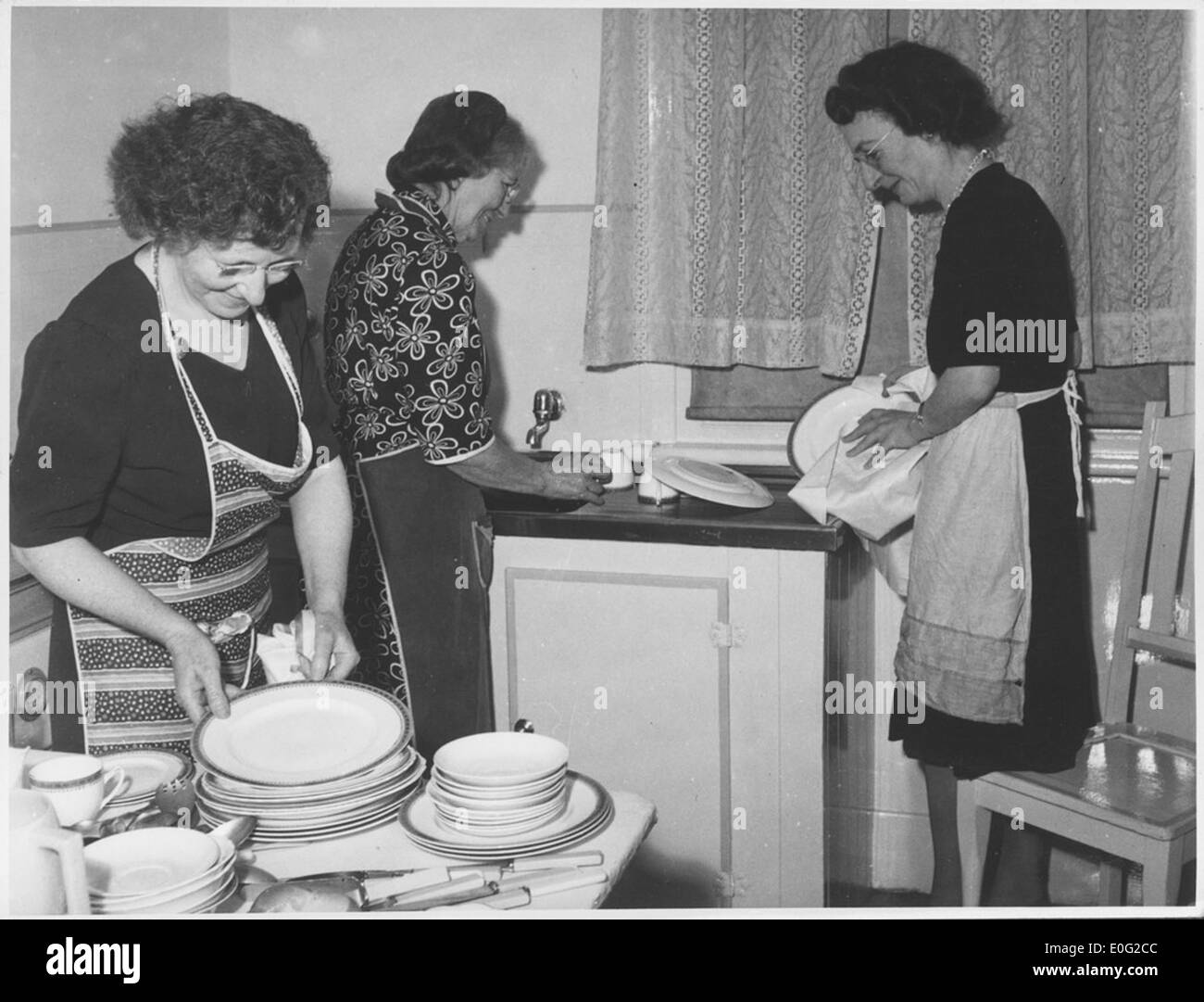 Three women washing and wiping dishes in a kitchen in Drouin, Victoria ...