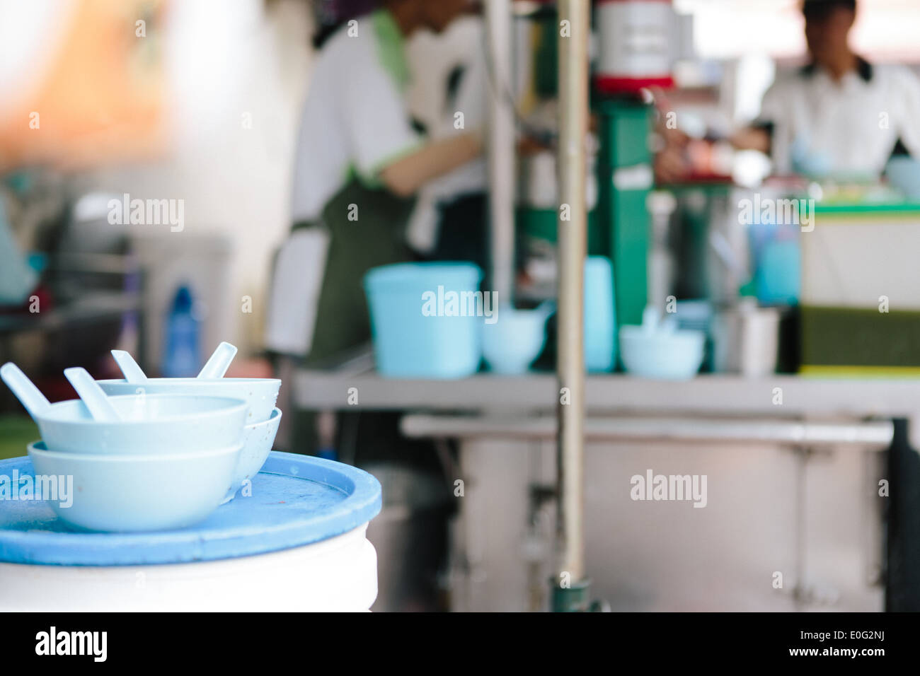 Foreground of empty blue bowls in front of a hawker stand in Penang ...