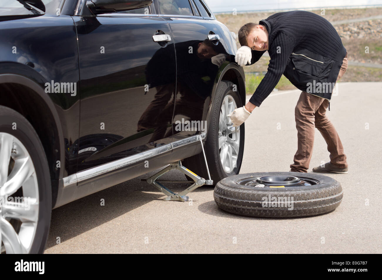 Male driver struggling to change his car tyre Stock Photo - Alamy