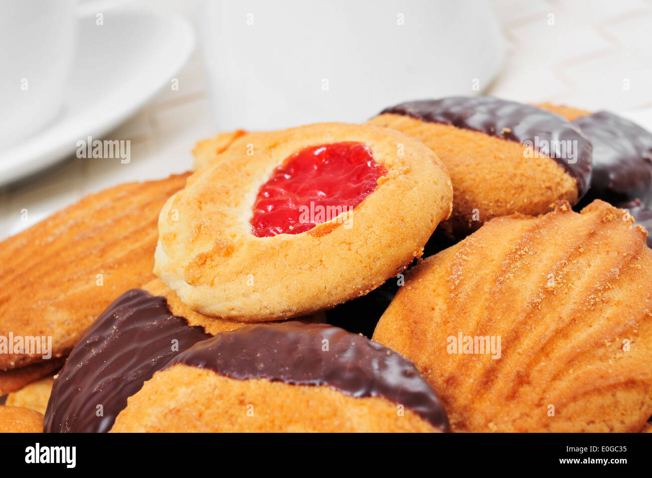closeup of some biscuits in a plate, on a set table with a cup of tea ...