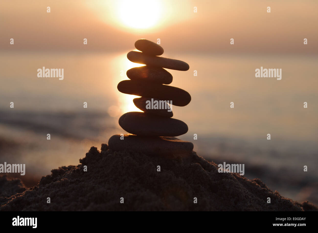 stone in sand on sunset background Stock Photo - Alamy