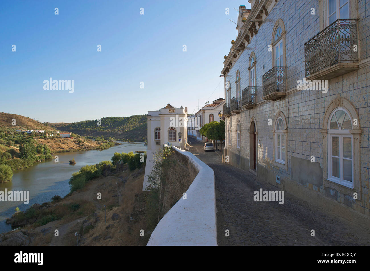 Street and houses above Rio Guadiana river at Mertola, Alentejo, north ...