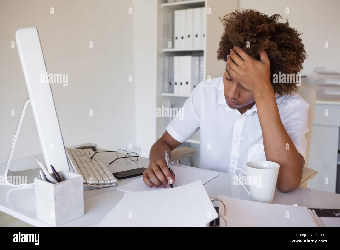 Casual stressed businessman writing at his desk Stock Photo - Alamy