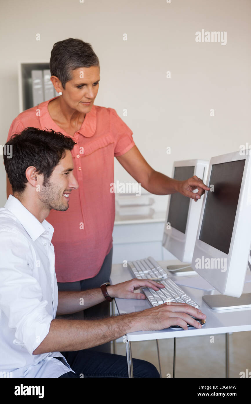 Casual business team working together at desk using computer Stock ...