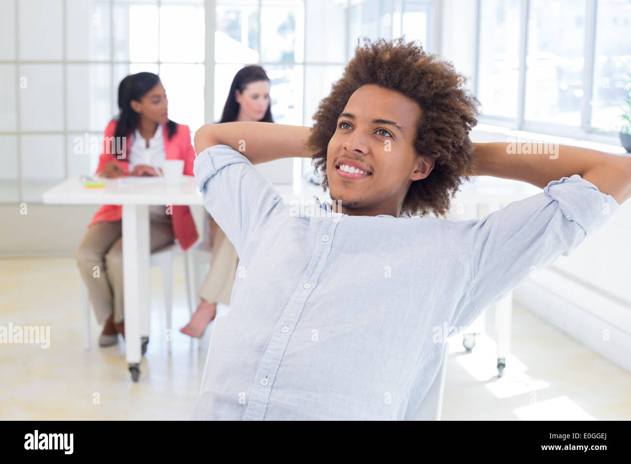 Businessman relaxing with coworkers behind him Stock Photo - Alamy