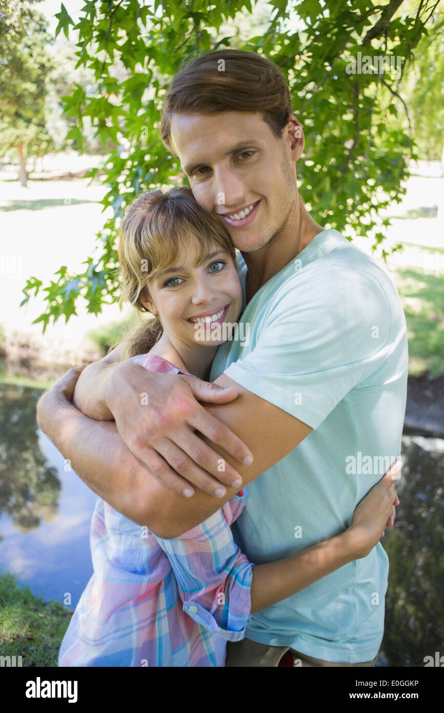 Close Young Couple Standing Together In The Park Smiling At Camera
