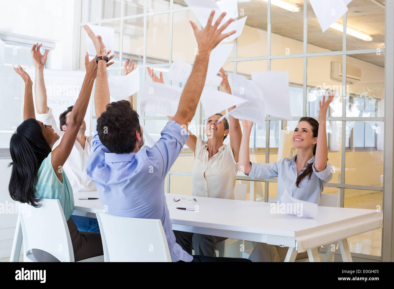 Cheerful workers throwing paper and smiling Stock Photo - Alamy