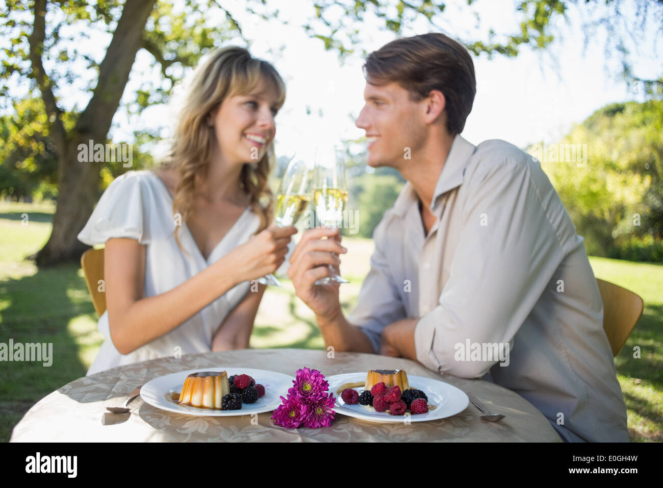 Cute happy couple sitting outside toasting with champagne with dessert ...