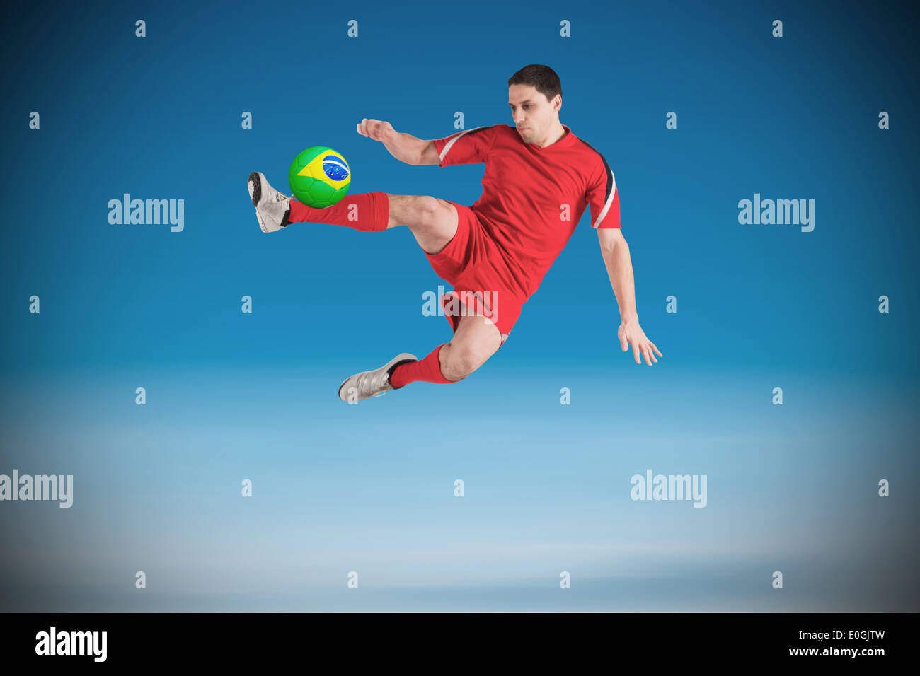 Fit football player jumping and kicking Stock Photo - Alamy