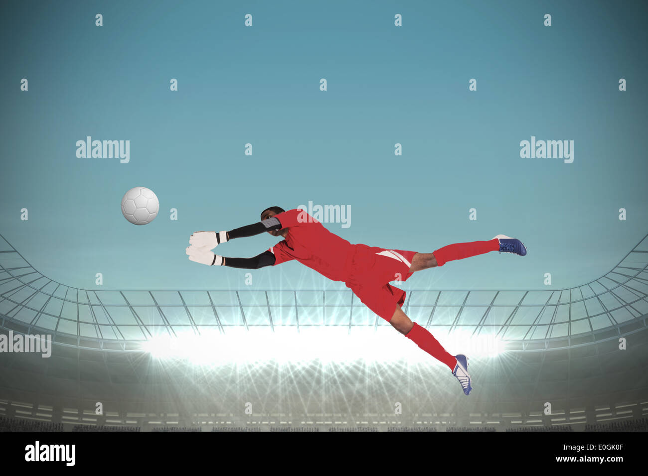 Goalkeeper in red making a save Stock Photo - Alamy