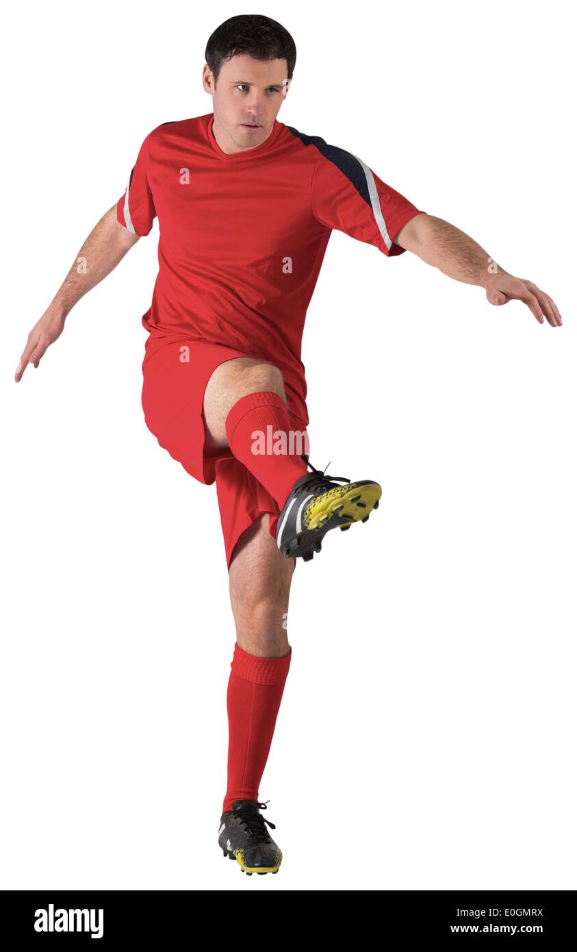 Football player in red kicking against black background with spark ...