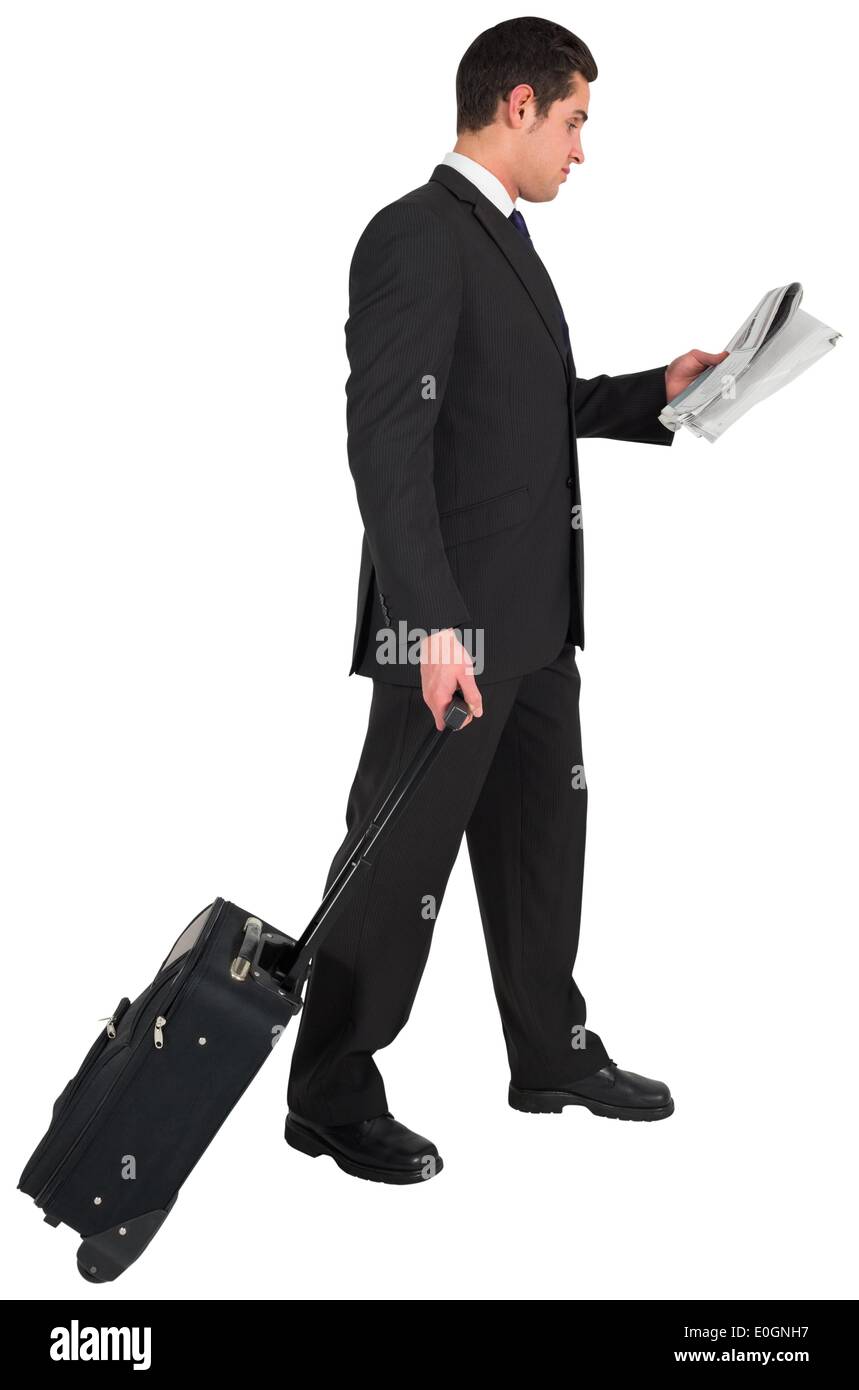 Businessman pulling his suitcase holding newspaper Stock Photo - Alamy