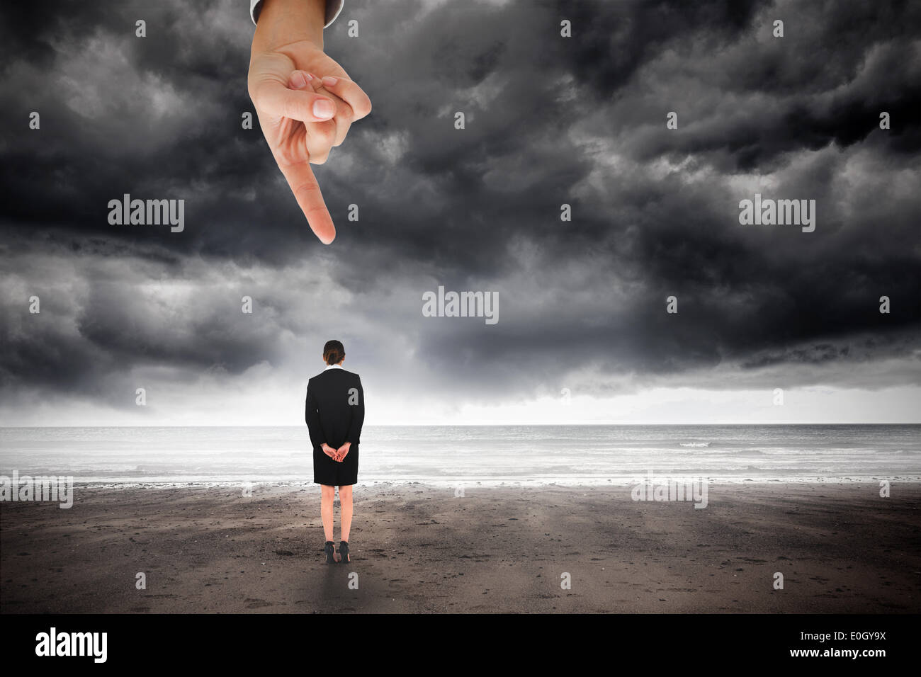 Giant hand pointing at young businesswoman standing with hands behind ...