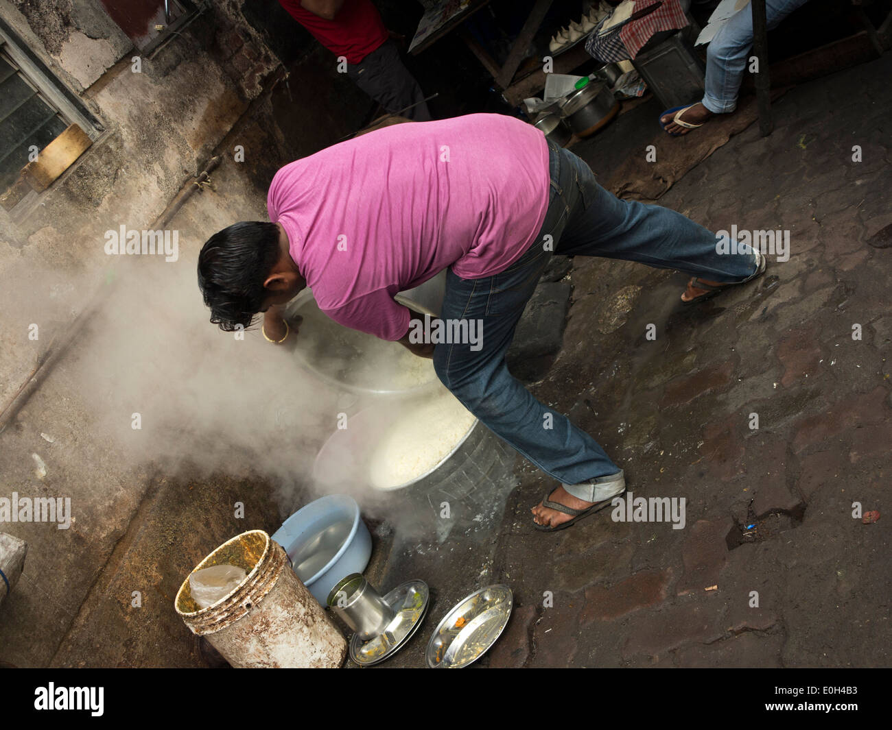 India, Mumbai, Fort District, street food, man straining rice through ...