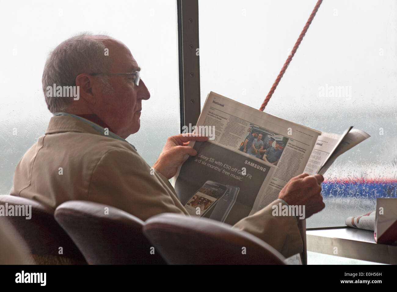 Man sat on ferry reading newspaper Stock Photo - Alamy