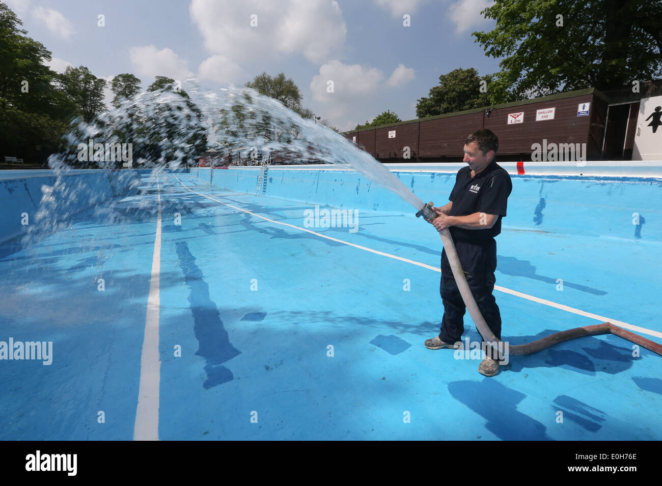 A man filling an outdoor swimming pool with a hose Stock Photo - Alamy