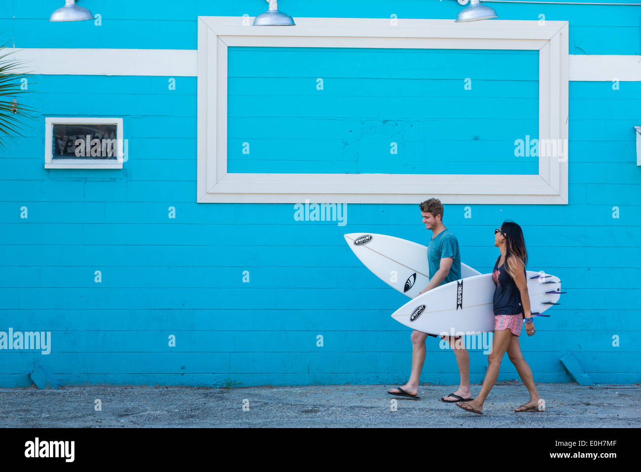 Two young surfers walk past a blue wall in Folly Beach, SC Stock Photo ...