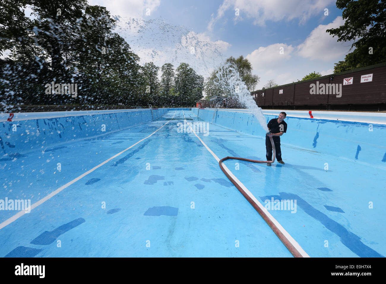 A man filling an outdoor swimming pool with a hose Stock Photo - Alamy