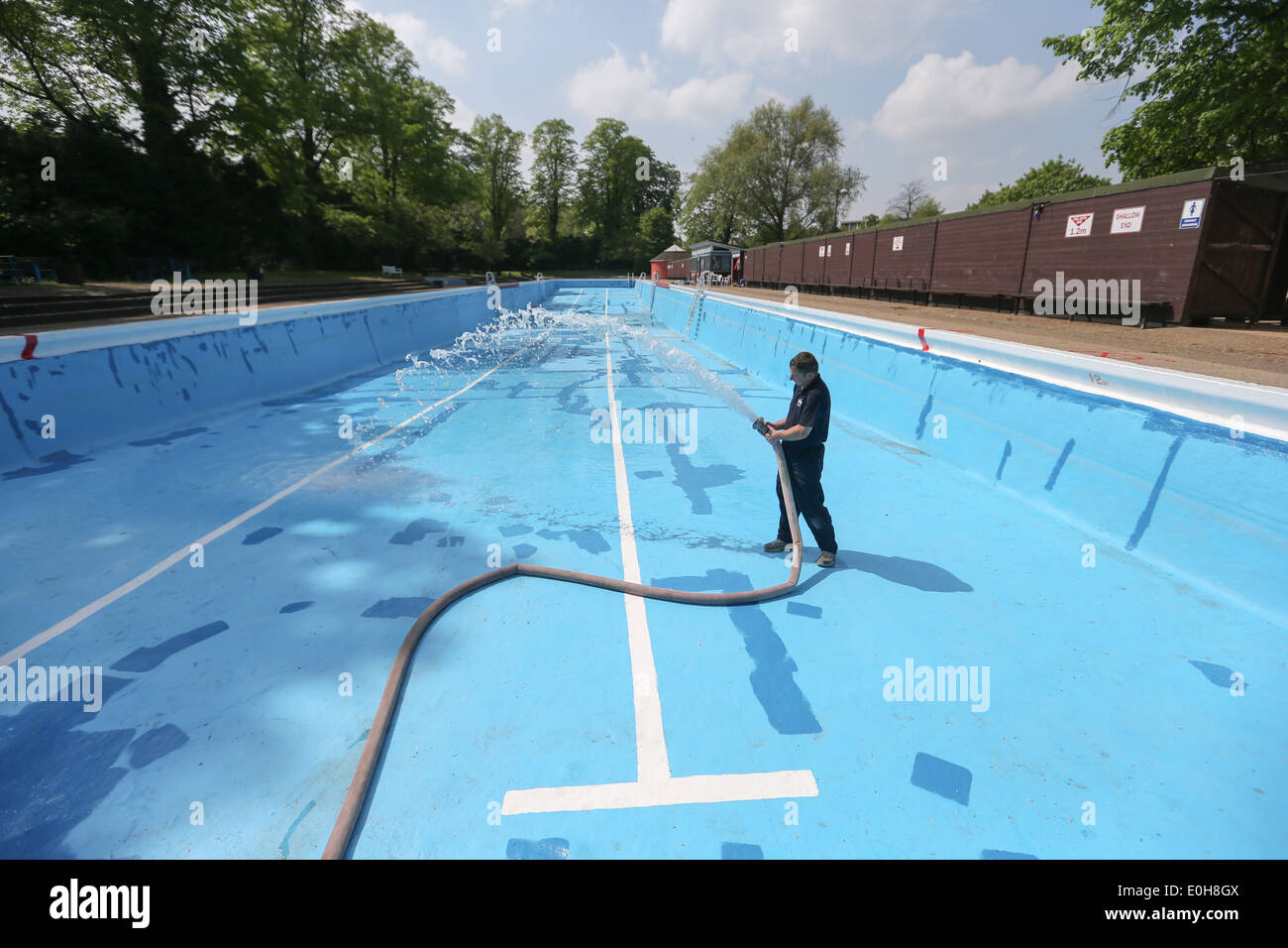 A man filling an outdoor swimming pool with a hose Stock Photo - Alamy