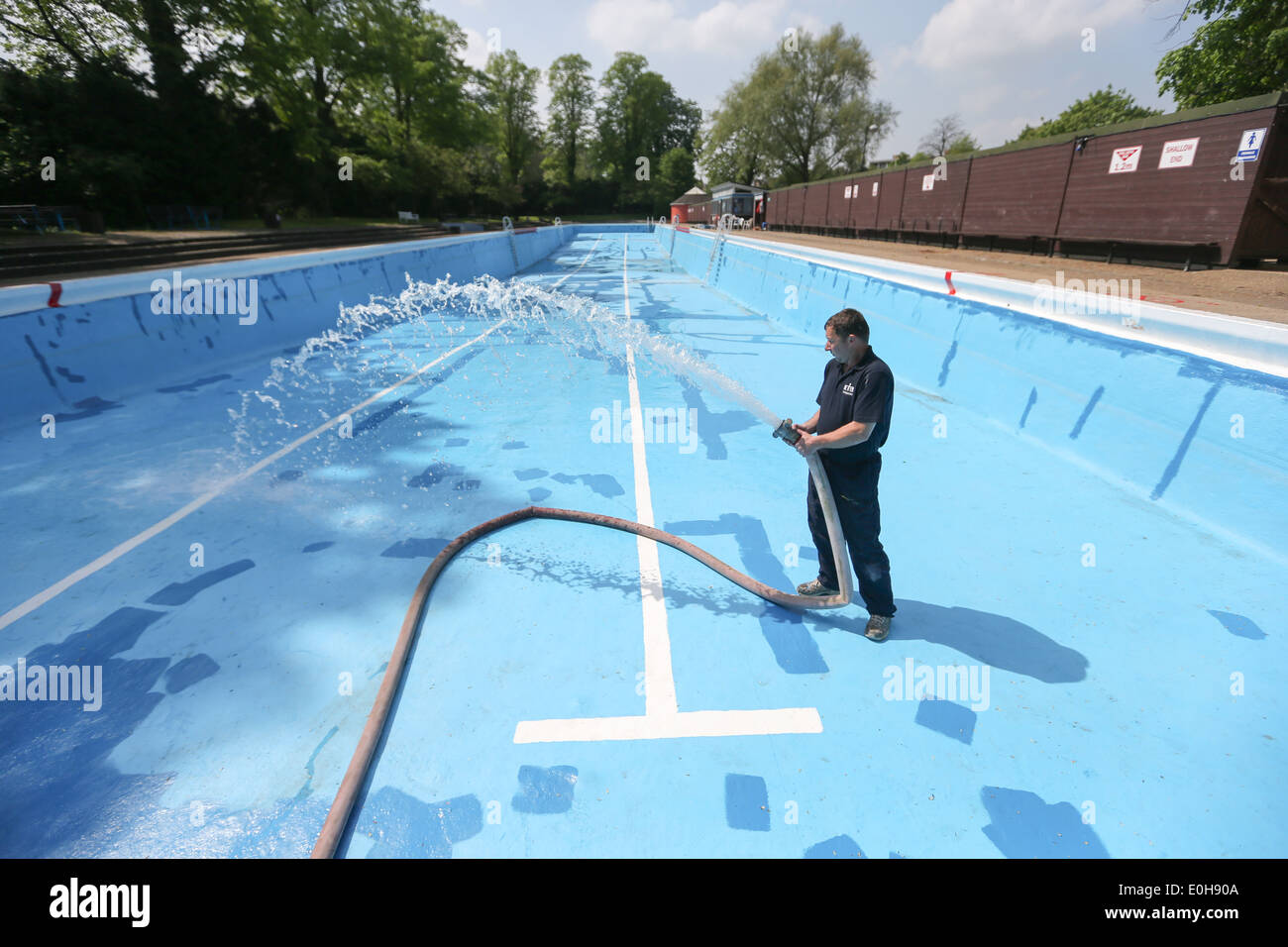 A man filling an outdoor swimming pool with a hose Stock Photo - Alamy
