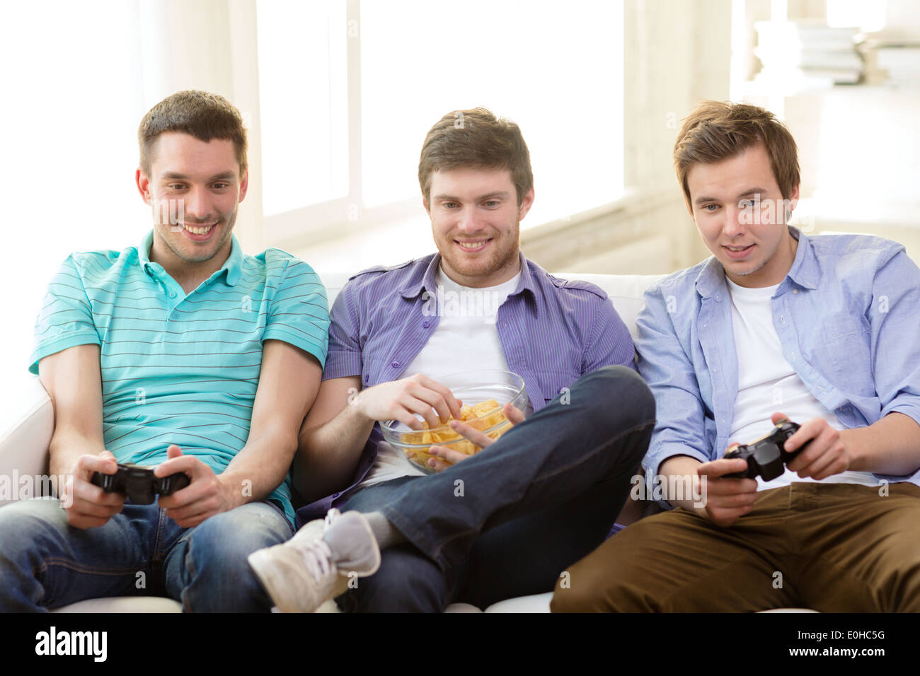 smiling friends playing video games at home Stock Photo - Alamy